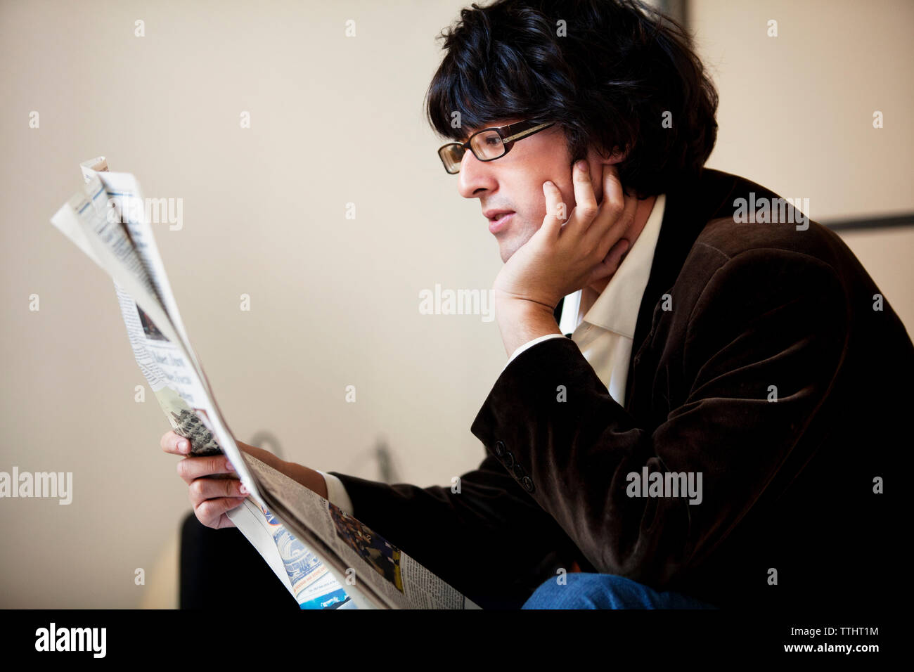 Side view of businessman reading newspaper at office Stock Photo - Alamy
