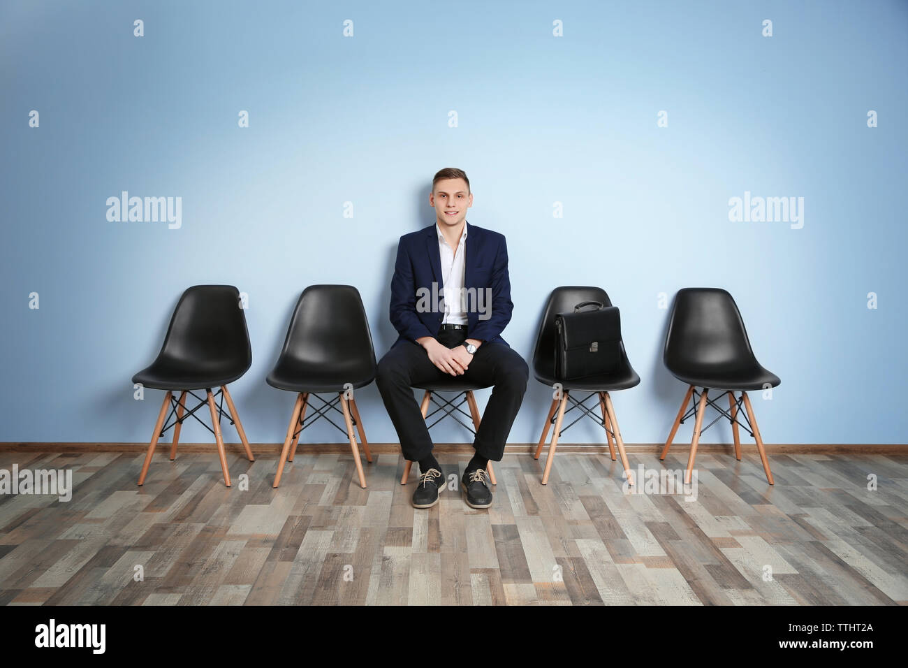 Young man in suit sitting on chair and waiting for job interview Stock ...