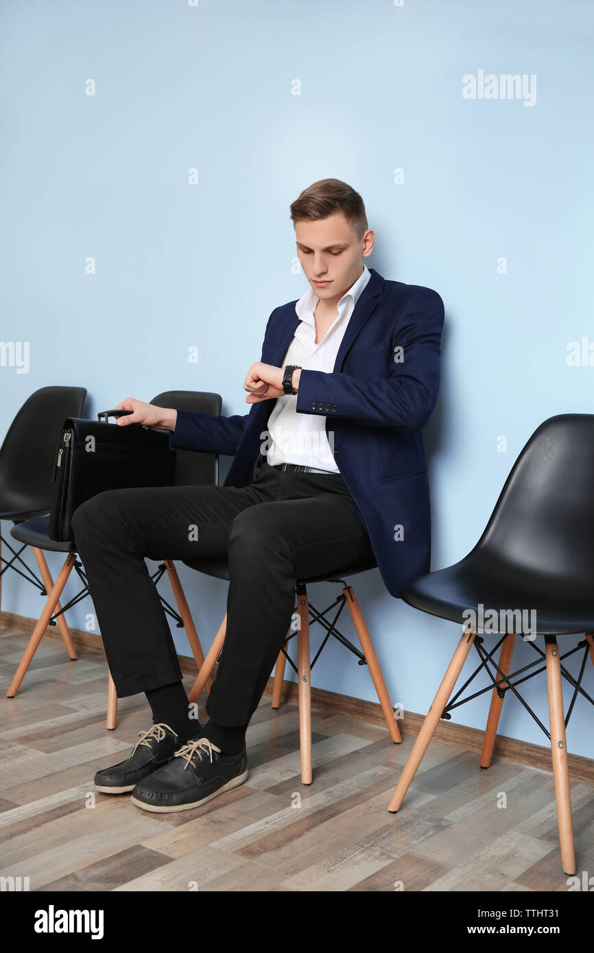 Young man in suit sitting on chair and waiting for job interview Stock ...