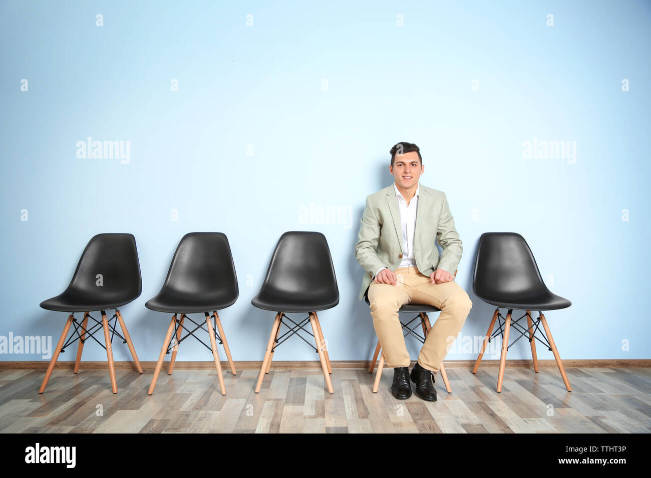 Young man in suit sitting on chair and waiting for job interview Stock ...