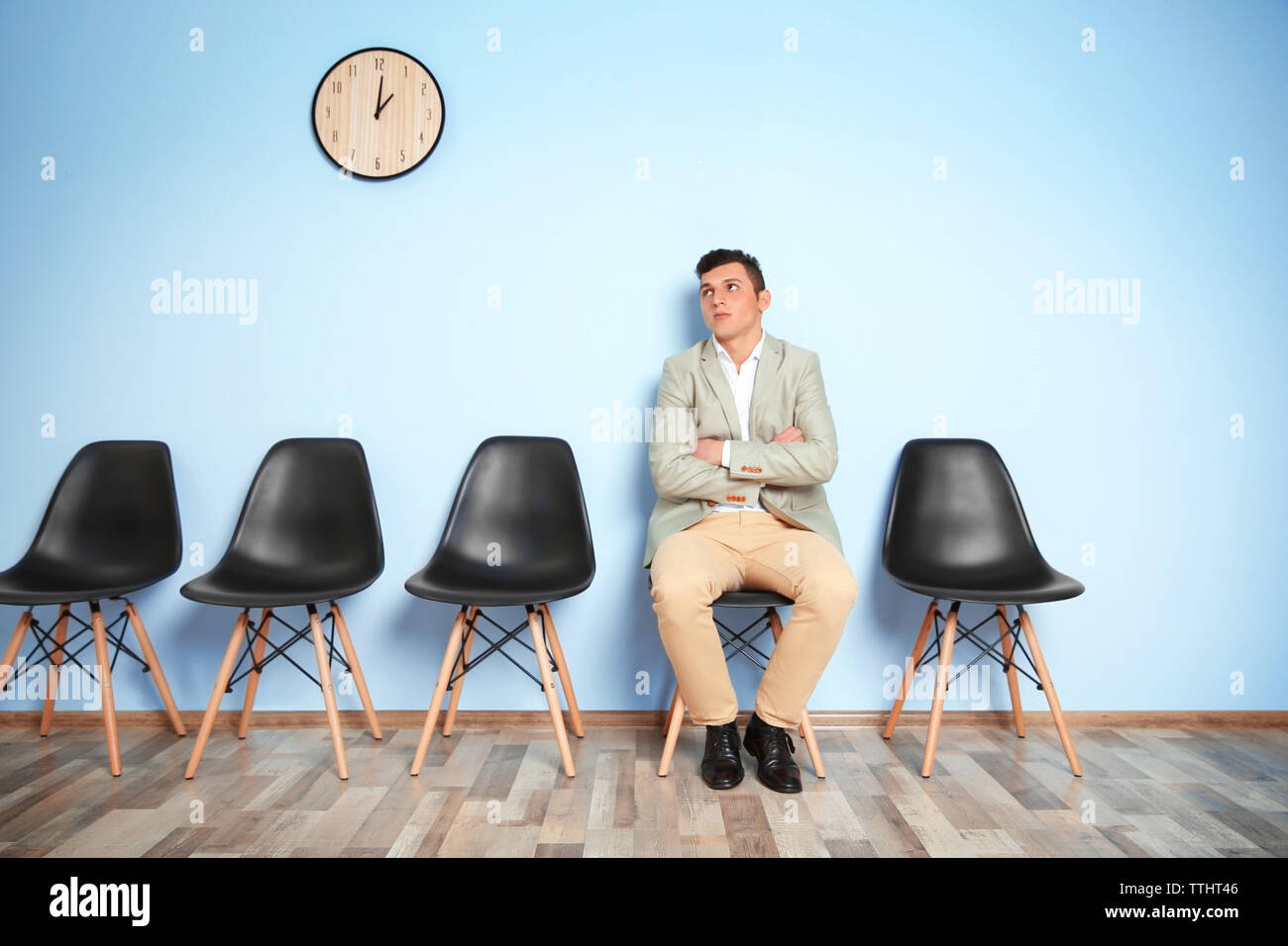 Young man in suit sitting on chair and waiting for job interview Stock ...