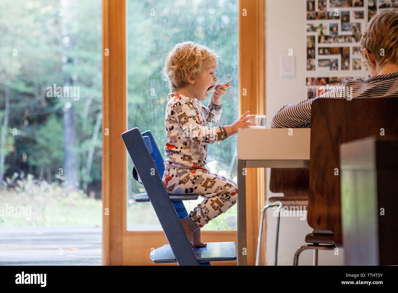 Side view of boy eating at dining table in home Stock Photo - Alamy