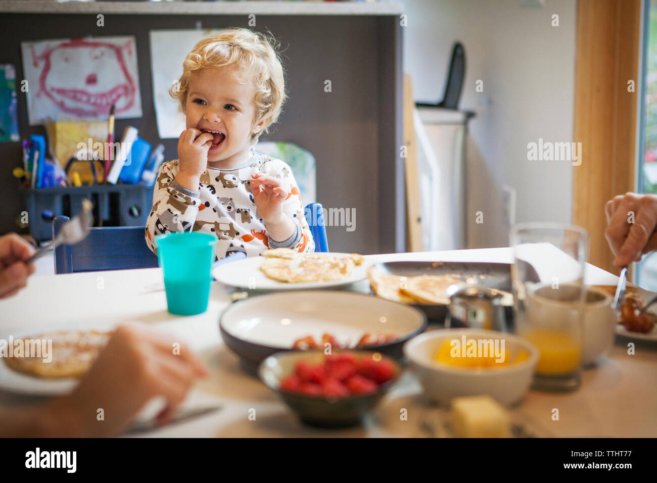 Happy boy eating breakfast at table in home Stock Photo - Alamy