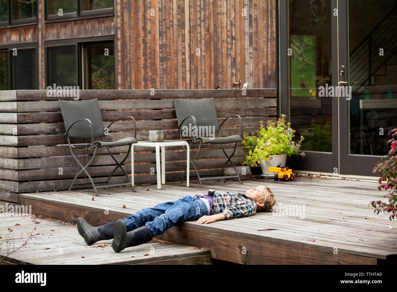 Boy lying down on porch outside house Stock Photo - Alamy