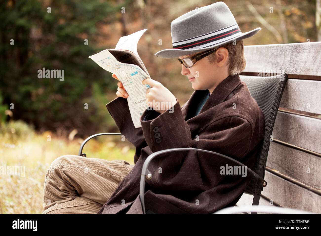 Boy reading newspaper while sitting on chair Stock Photo - Alamy