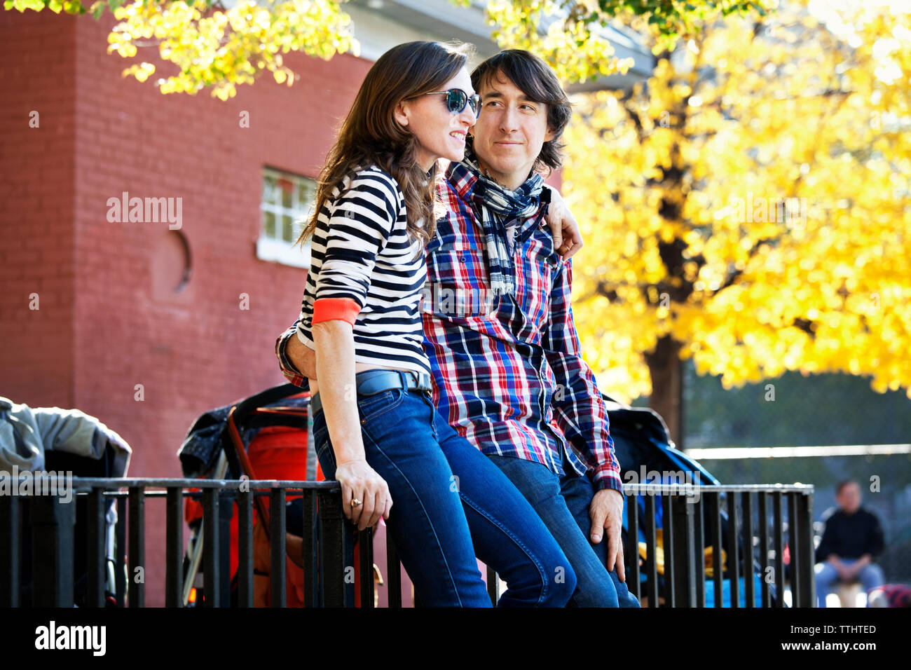 Couple with arm around leaning on railing Stock Photo - Alamy