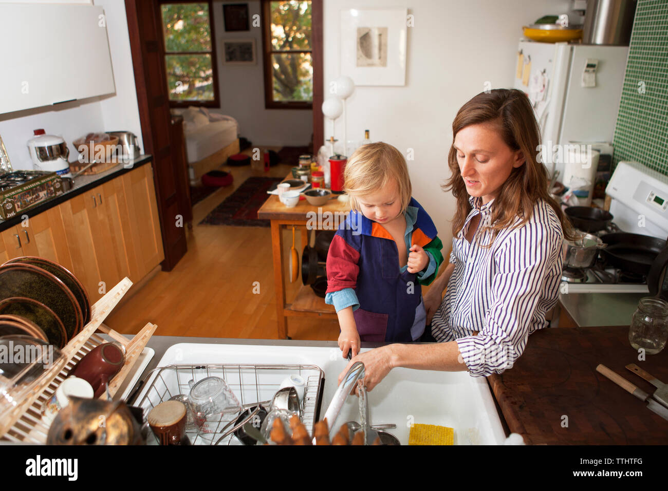 Family washing utensils in kitchen sink hi-res stock photography and ...