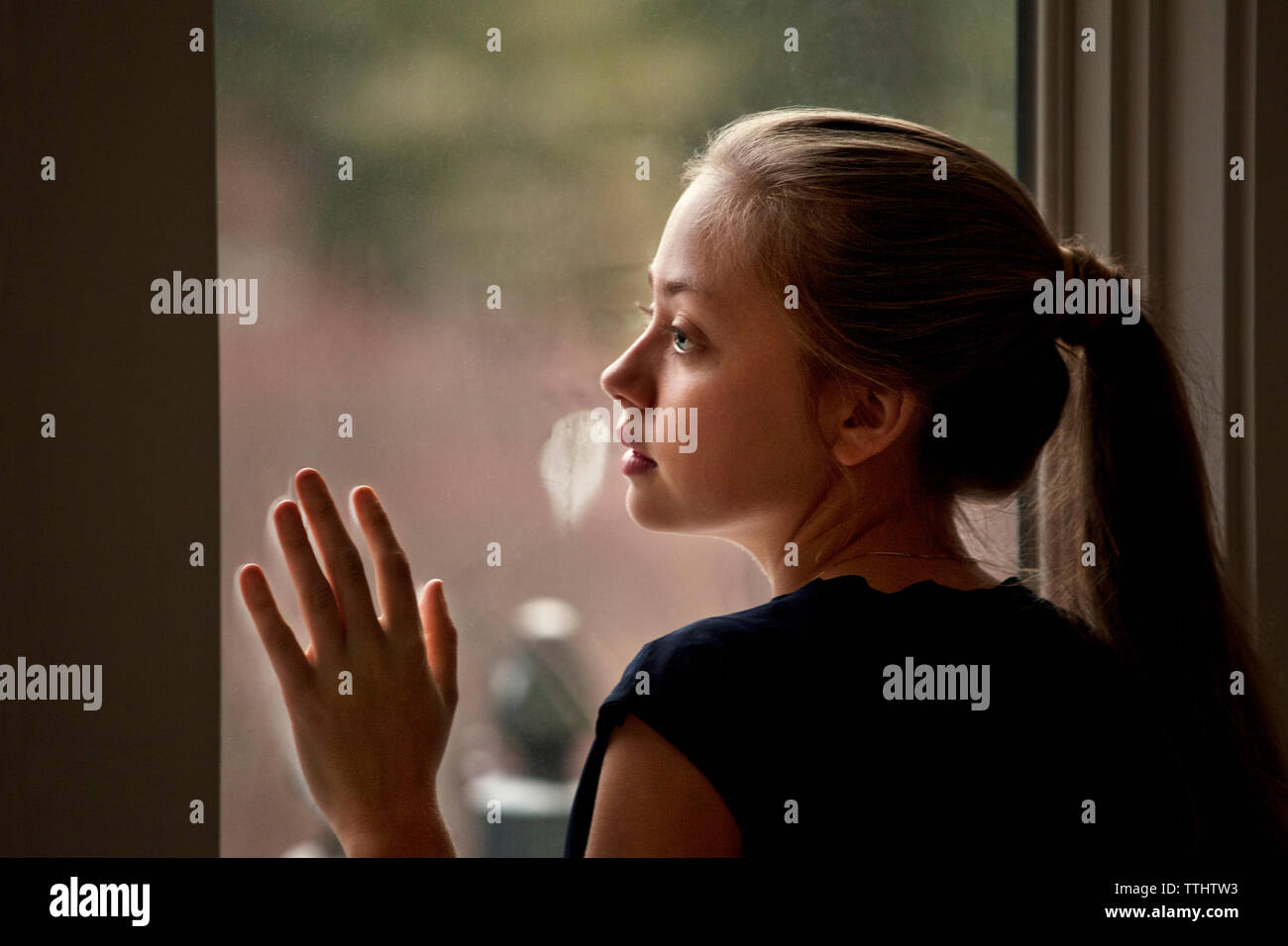 Woman leaning on window glass at home Stock Photo - Alamy