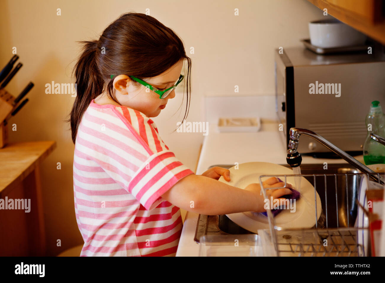 Girl washing plate in kitchen sink Stock Photo - Alamy