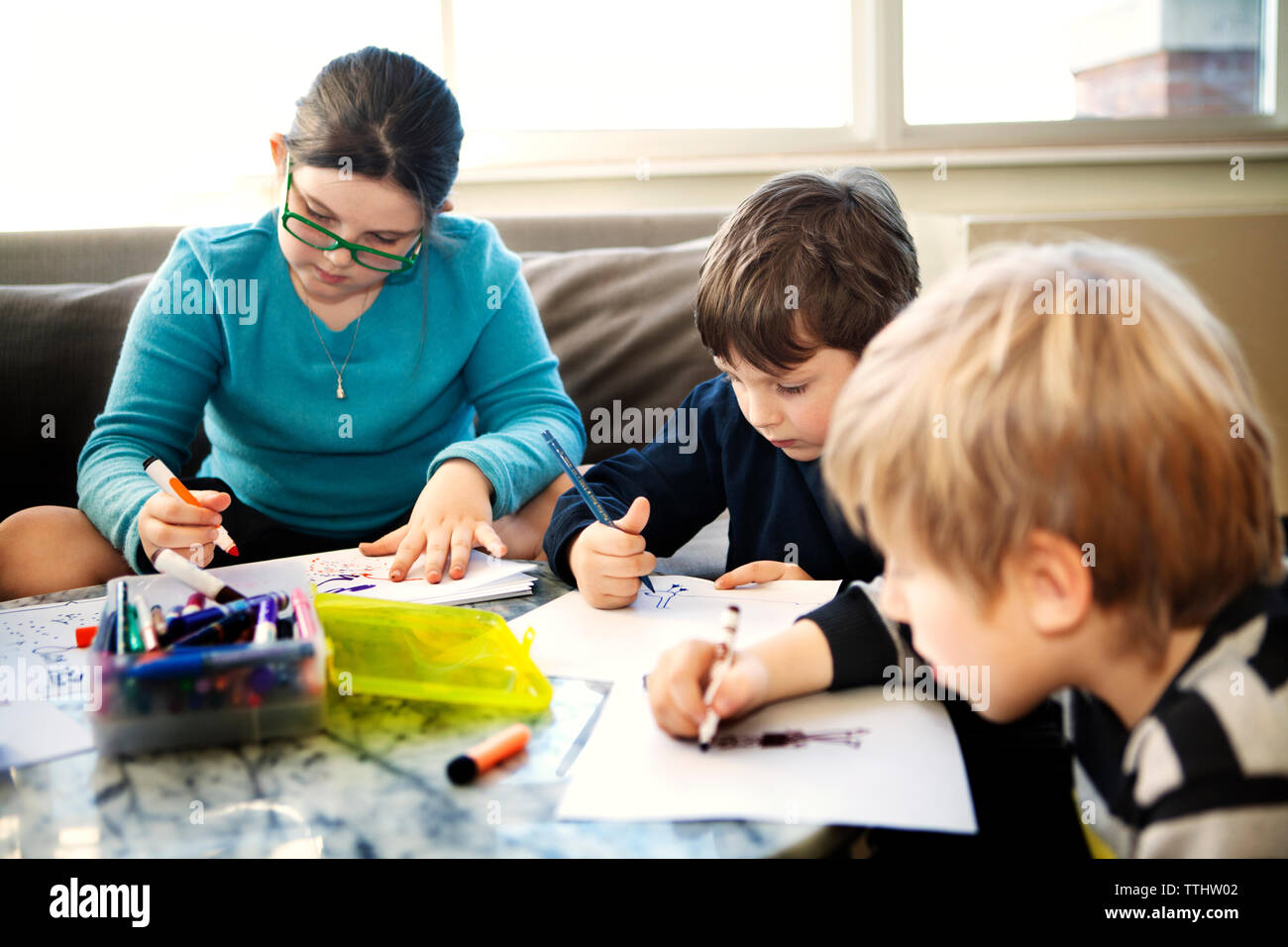 Children drawing on paper while sitting at home Stock Photo - Alamy