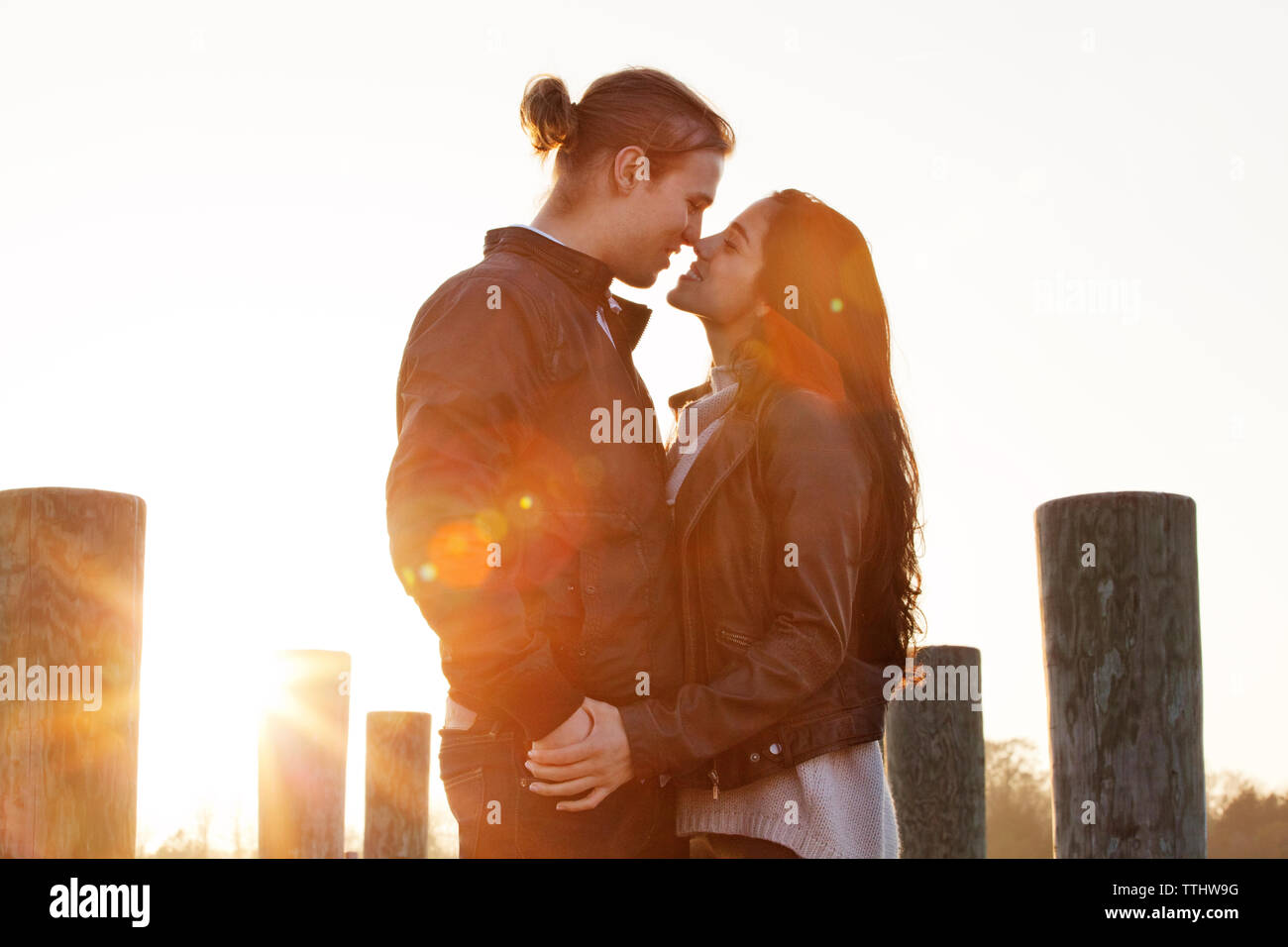 Romantic couple standing on pier during sunset Stock Photo - Alamy