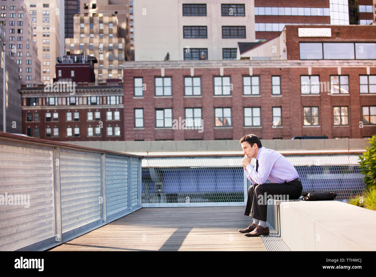 Side view of businessman sitting on retaining wall Stock Photo - Alamy
