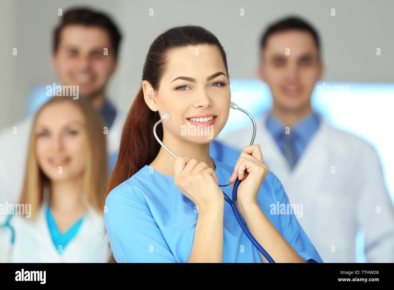 Smiling doctor with medical workers standing in hospital Stock Photo ...