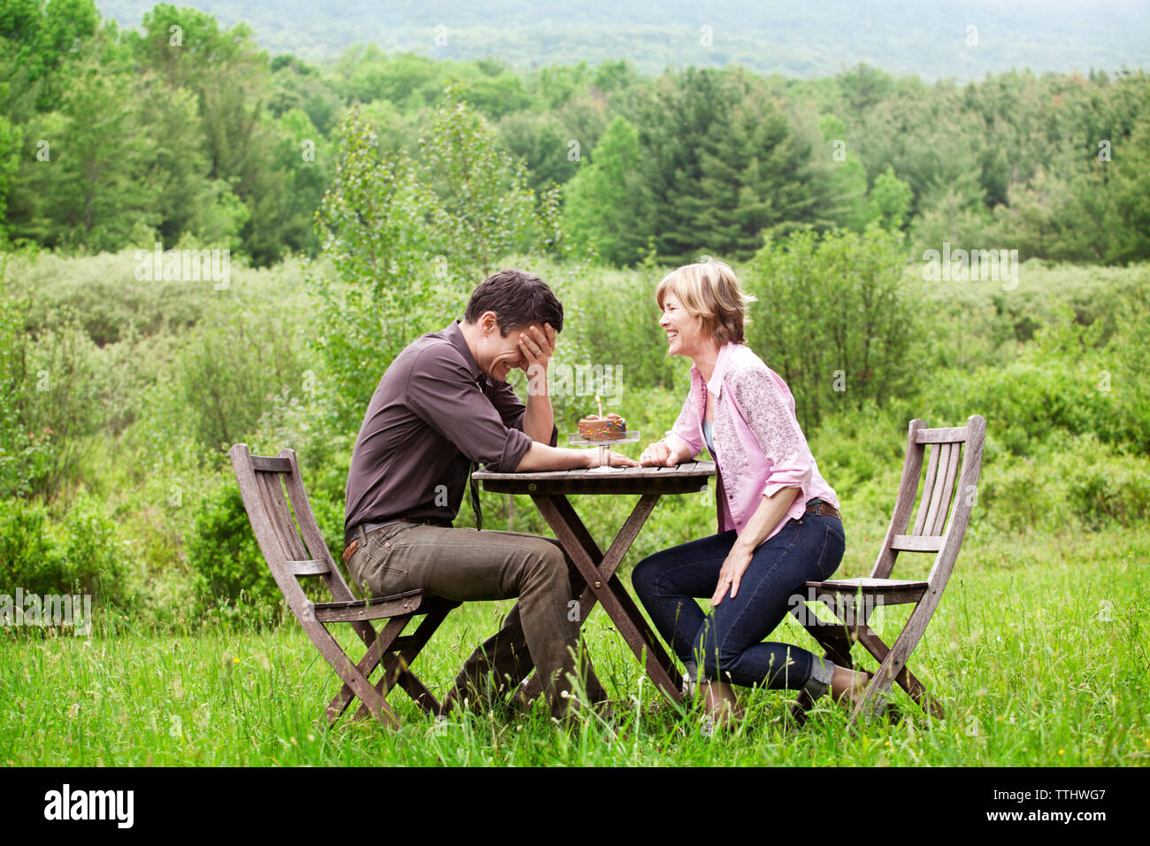 Side view of couple sitting on chair in field Stock Photo - Alamy