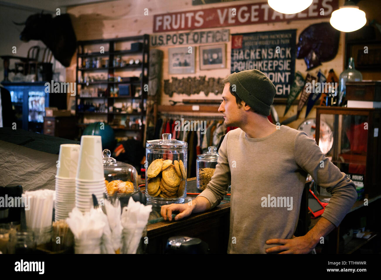 Man looking away while standing at counter in cafe Stock Photo - Alamy