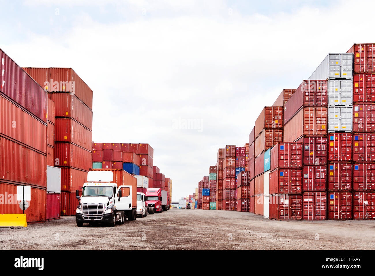 Semi-trucks on road by stack of cargo containers at commercial dock ...