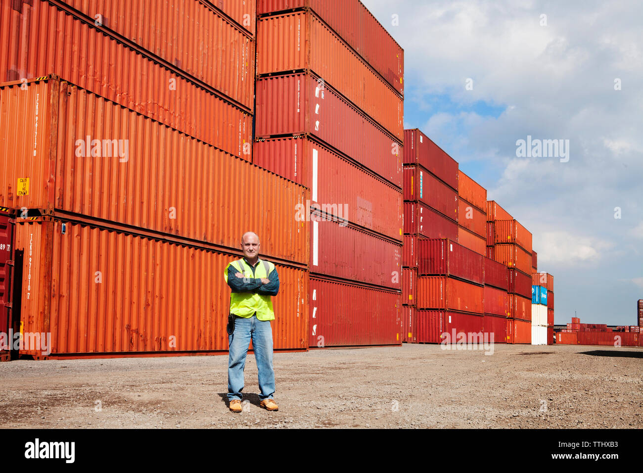 Portrait of confident man with arms crossed standing against cargo ...