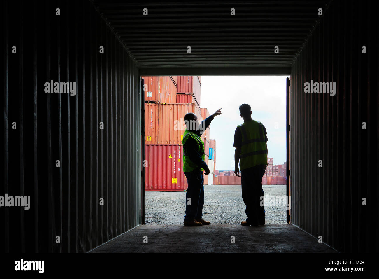Worker pointing away while standing with man by cargo container at ...