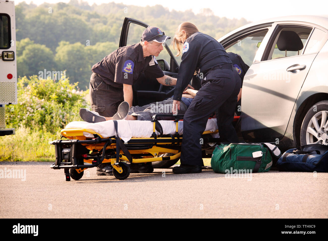 Paramedics putting patient on hospital gurney by car Stock Photo - Alamy