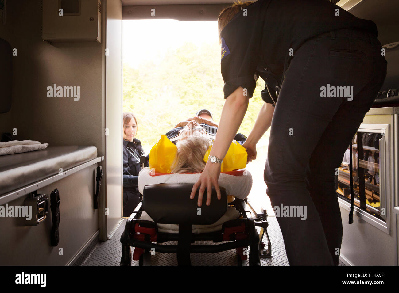 Paramedics pushing hospital gurney in ambulance Stock Photo - Alamy