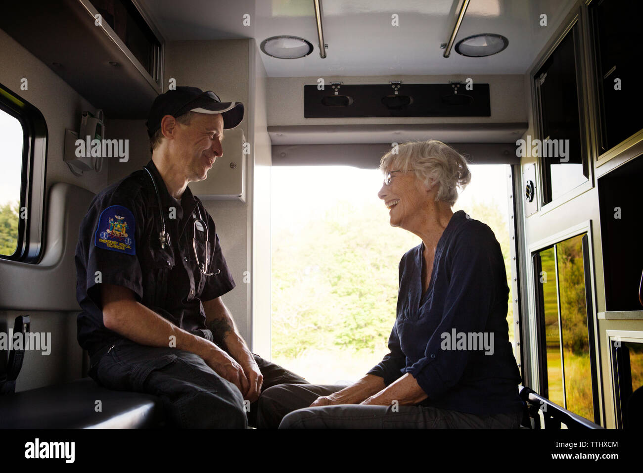 Paramedics laughing with patient while sitting in ambulance Stock Photo ...