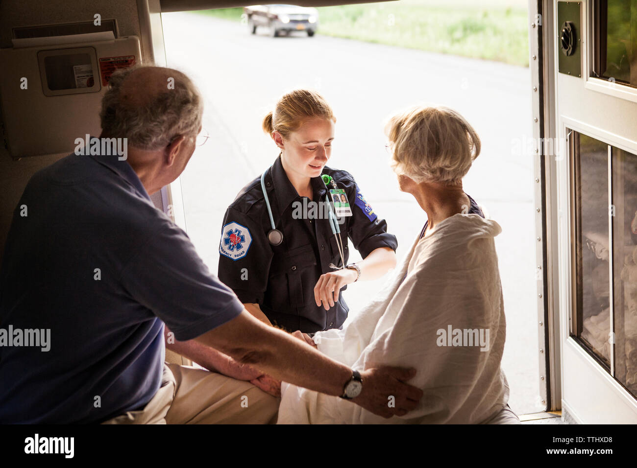 Paramedic checking pulse of patient by husband in ambulance Stock Photo ...