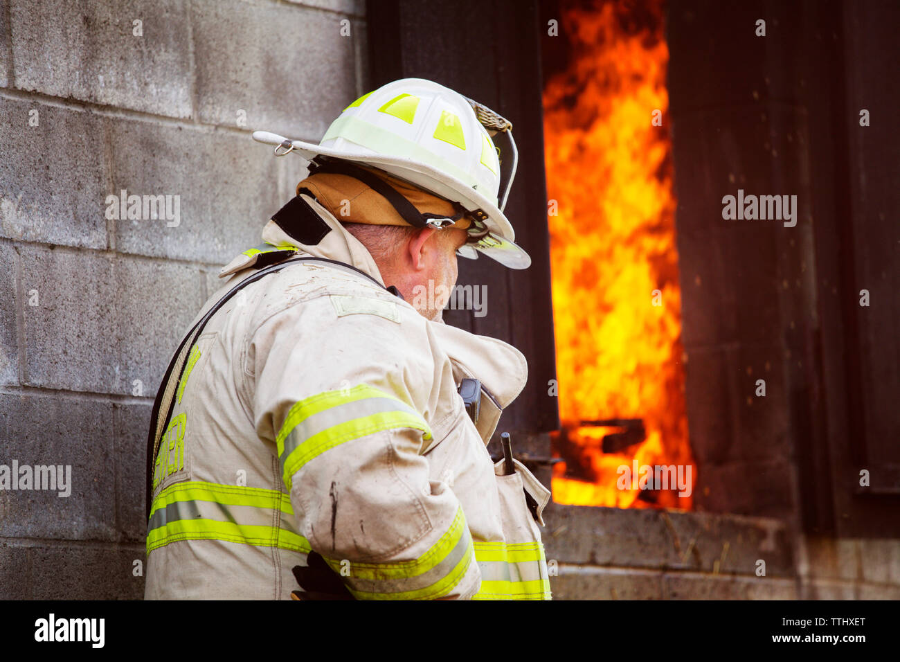 Firefighter standing by wall Stock Photo - Alamy