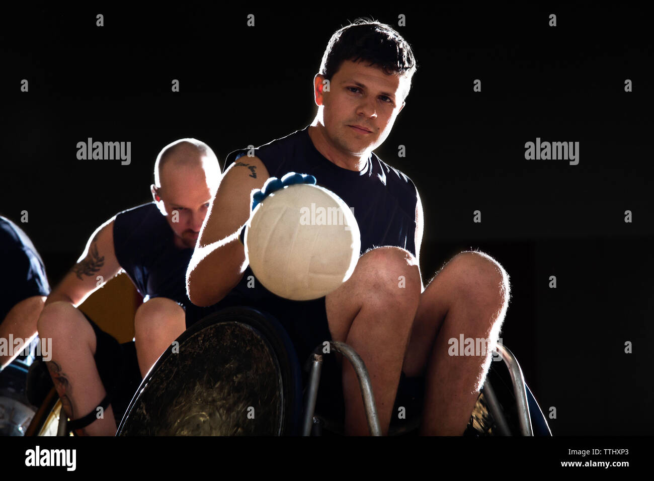 Portrait of man dribbling ball while playing wheelchair rugby in court ...