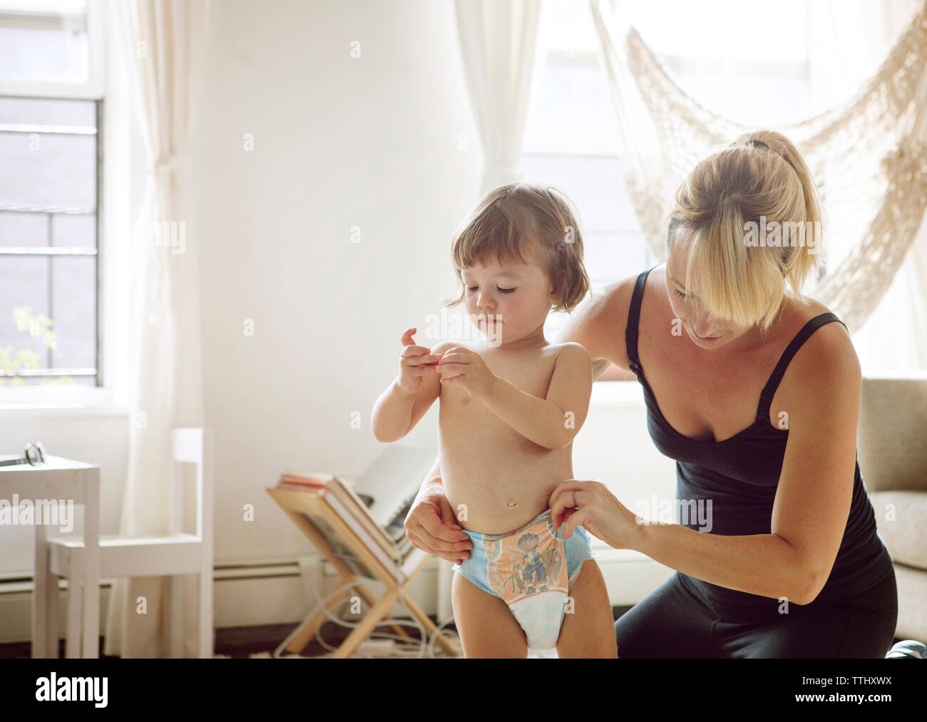 Mother dressing daughter at home Stock Photo - Alamy