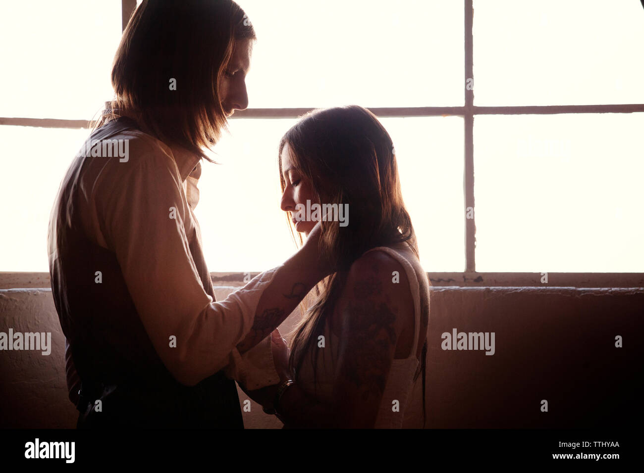 Side view of couple standing by window at home Stock Photo - Alamy