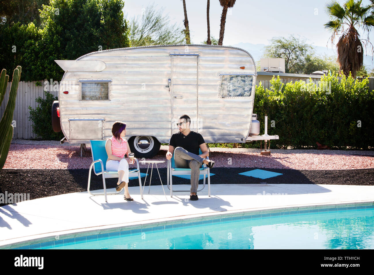 Couple sitting on chair by swimming pool against camper van Stock Photo ...