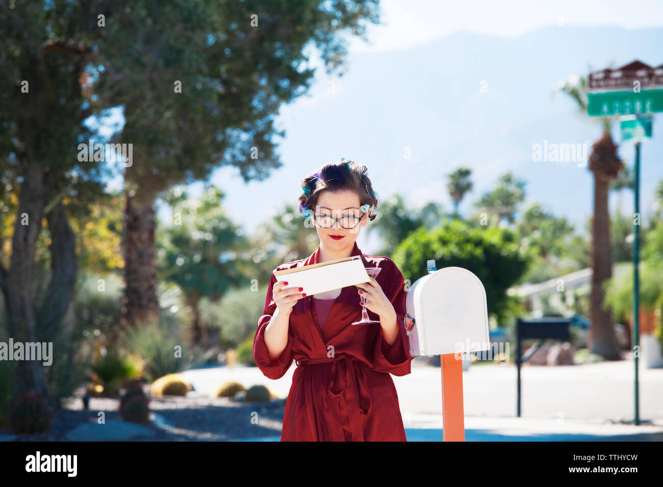 Woman reading mail while standing by mailbox Stock Photo - Alamy