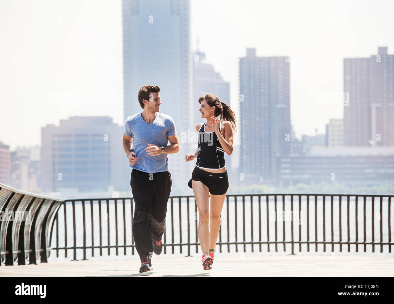 Couple jogging against railing Stock Photo - Alamy