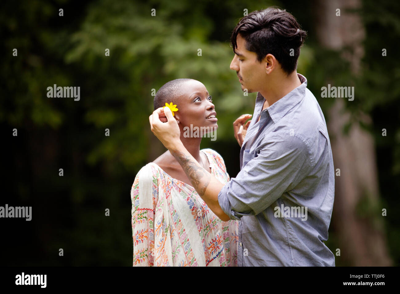 Side view of man putting flower in woman's ear Stock Photo - Alamy
