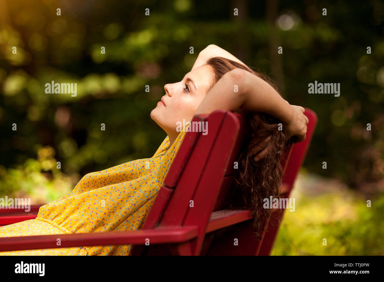 Side view of woman relaxing on lounge chair Stock Photo - Alamy