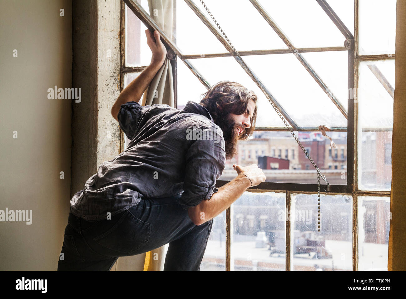 Man looking through window while standing at home Stock Photo - Alamy