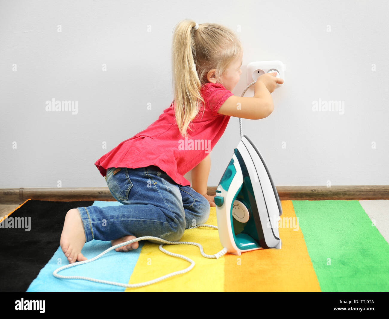 Little girl playing with iron in the kid's room Stock Photo - Alamy