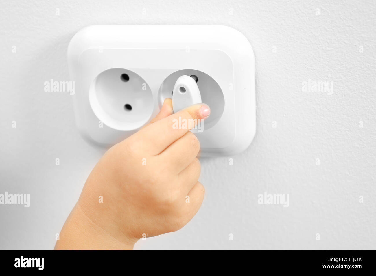 Little child putting plug in power socket Stock Photo - Alamy