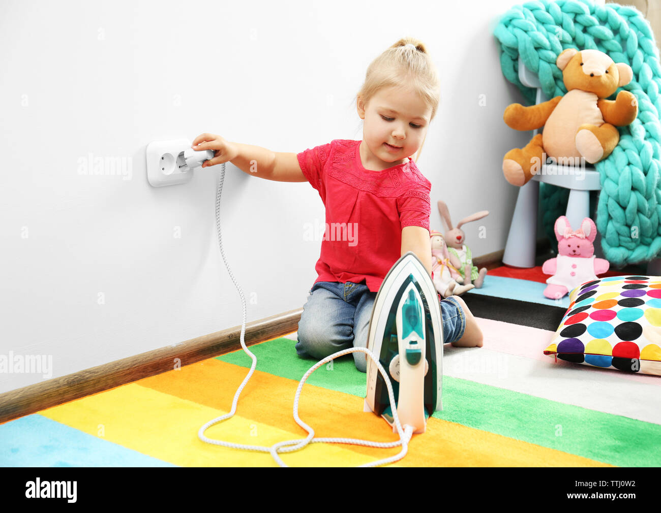 Little girl playing with iron in the kid's room Stock Photo - Alamy