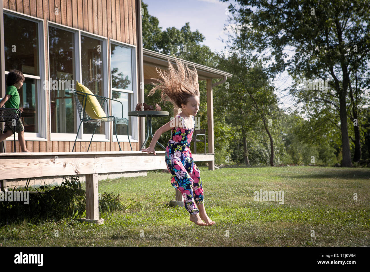Full length of girl jumping from porch Stock Photo - Alamy