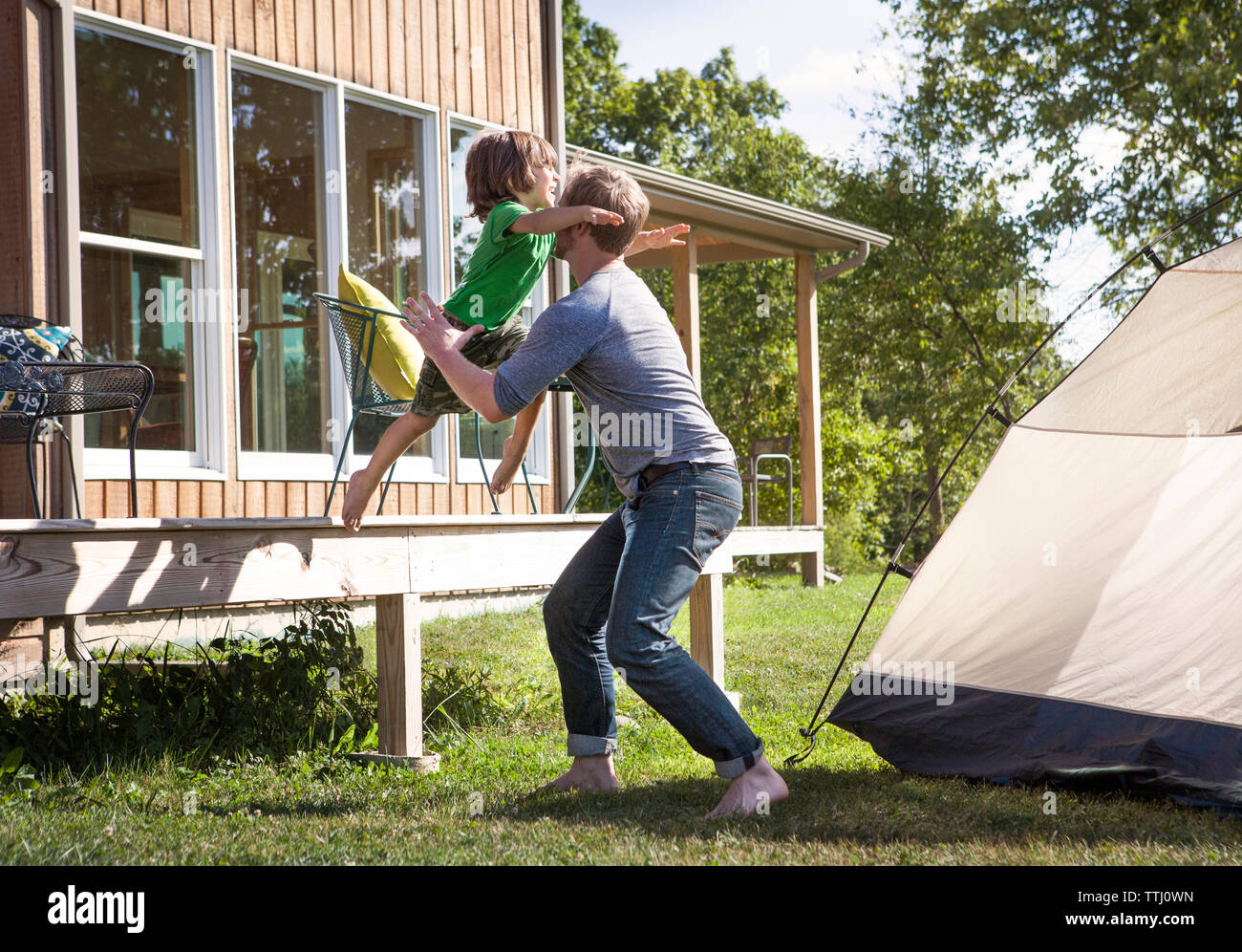Man catching boy jumping from porch Stock Photo - Alamy