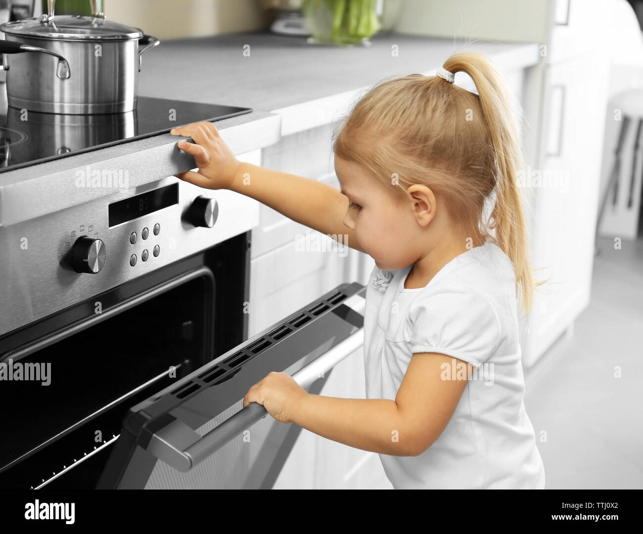 Little girl playing with oven in kitchen Stock Photo - Alamy