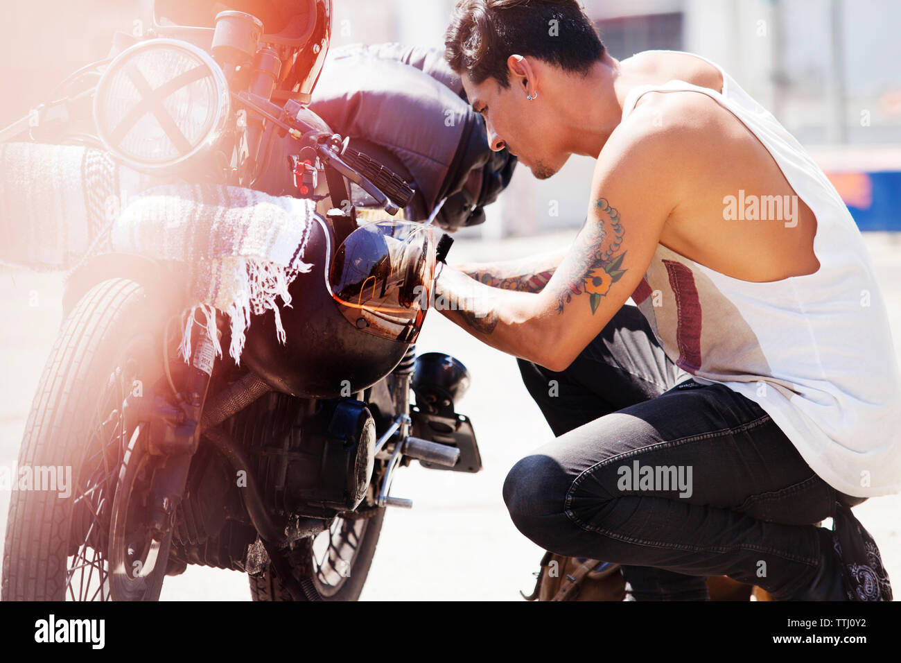 Side view of man looking at motorcycle engine Stock Photo - Alamy