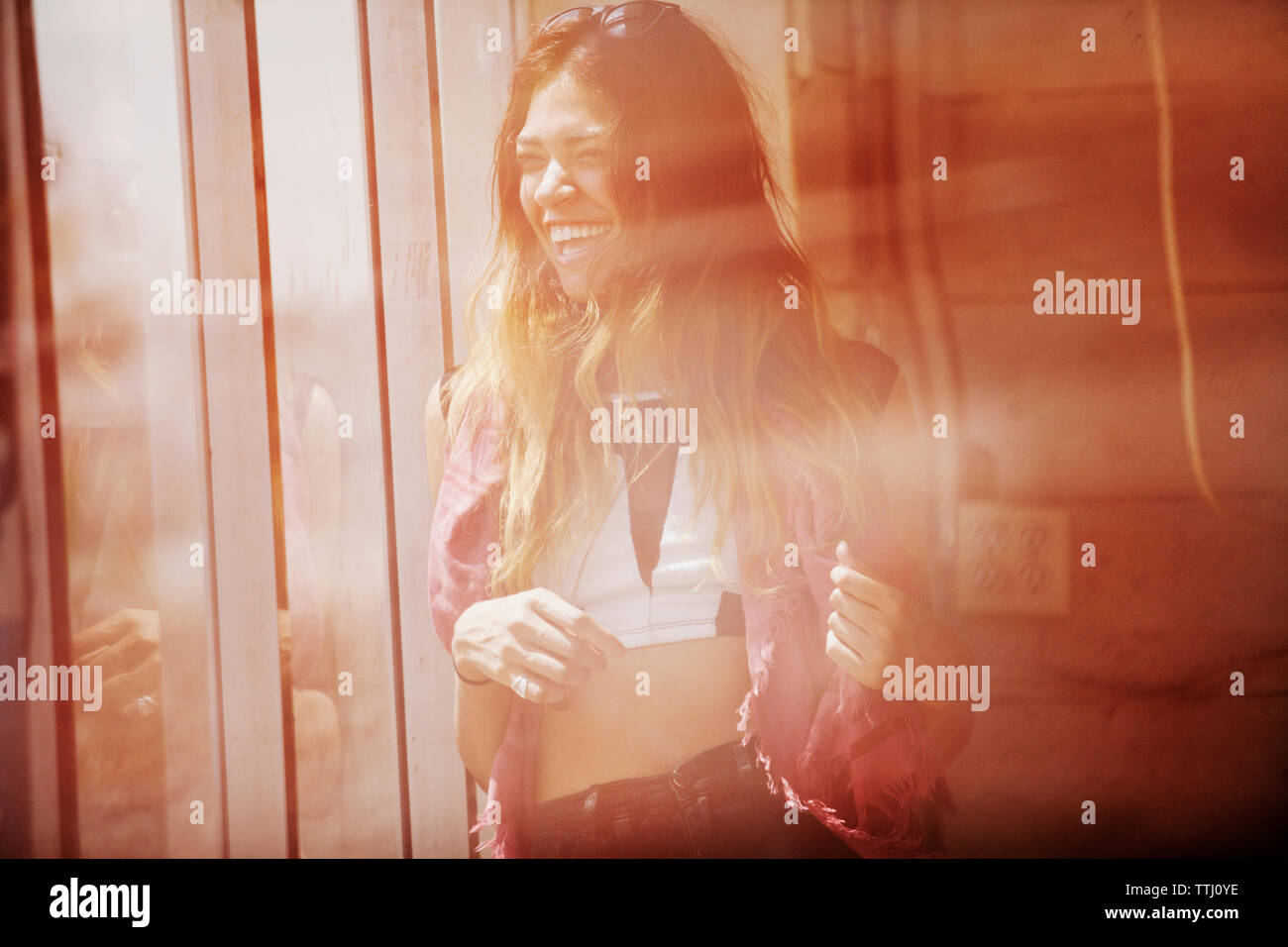 Cheerful woman standing by window on sunny day Stock Photo - Alamy