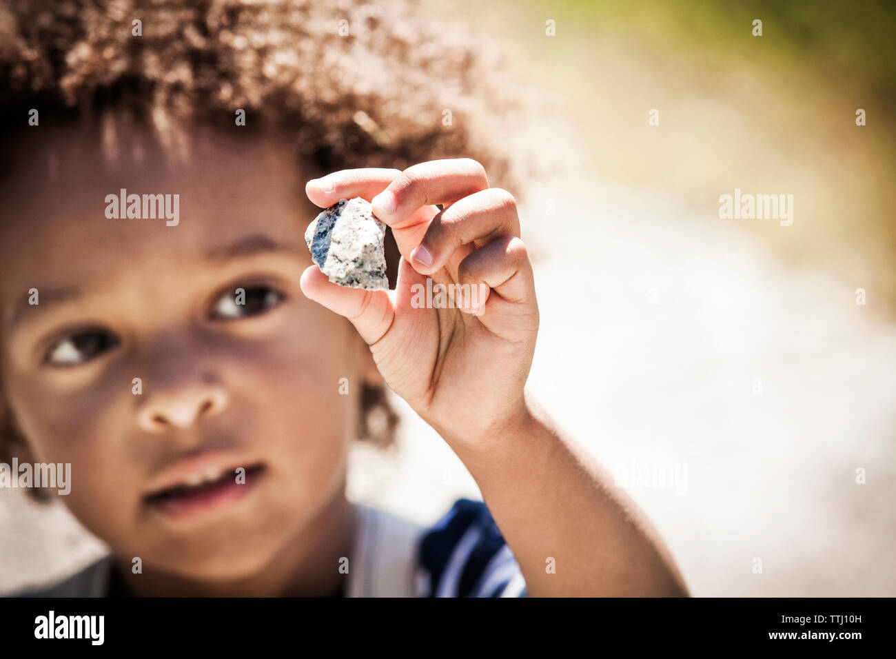 Boy showing stone at backyard Stock Photo - Alamy
