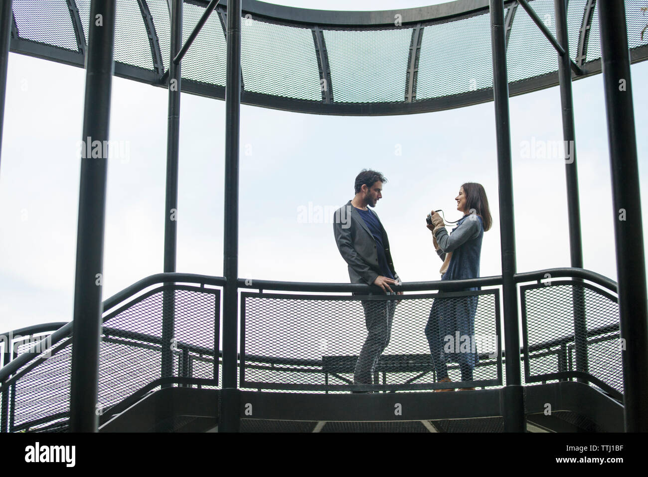 Woman photographing man while standing on footbridge Stock Photo - Alamy