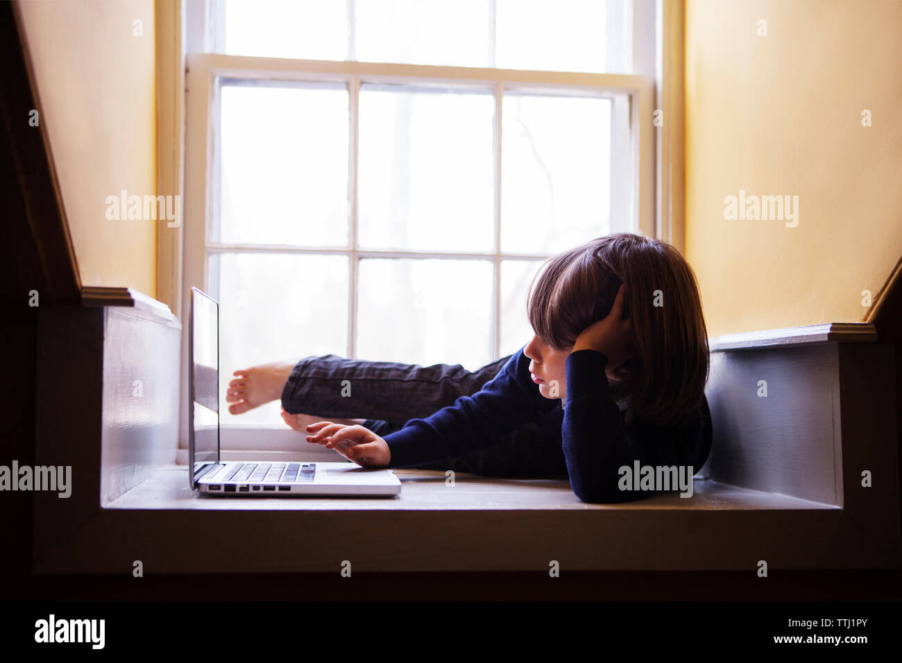 Boy using laptop computer while lying on floor at home Stock Photo - Alamy