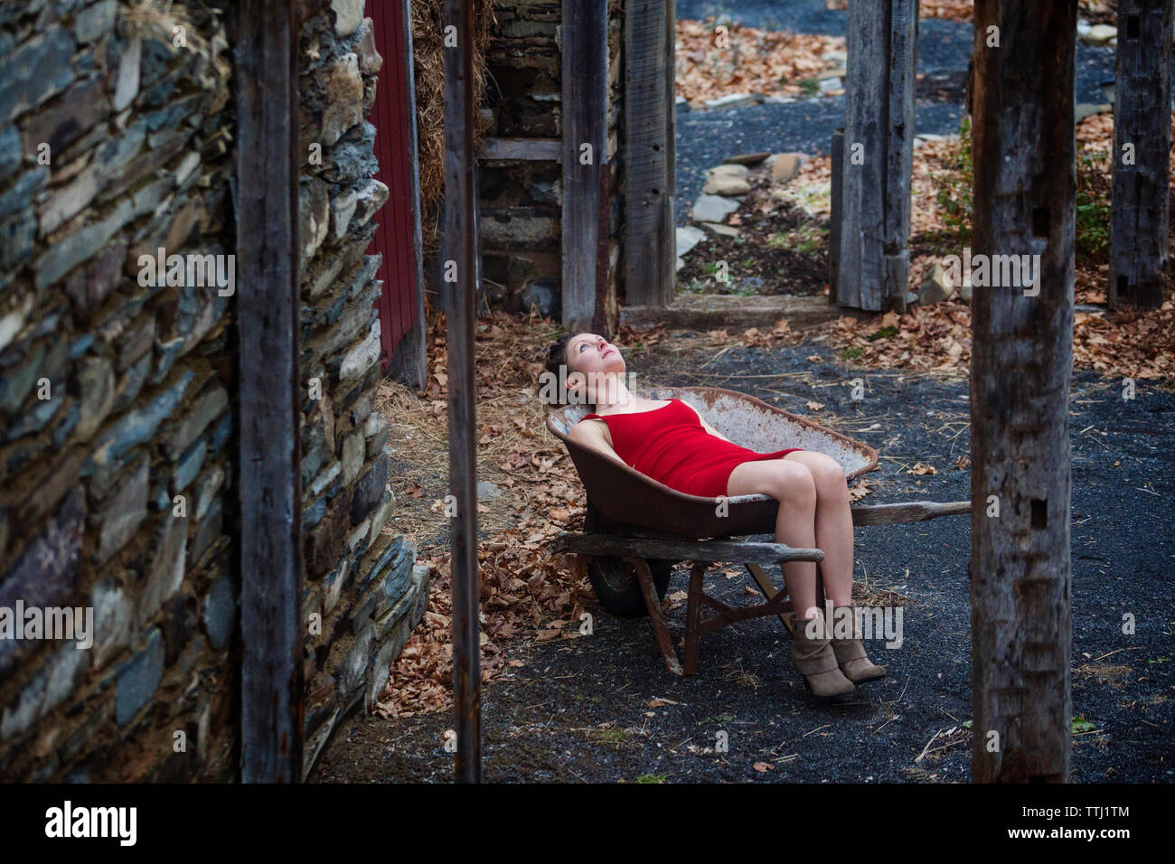 Thoughtful woman sitting in wheelbarrow Stock Photo - Alamy