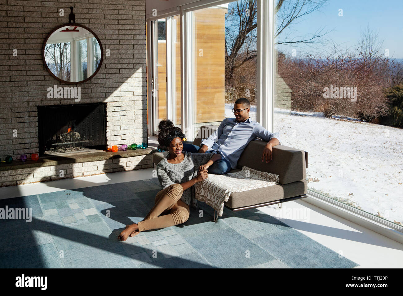 Happy couple sitting by window in living room at home Stock Photo - Alamy