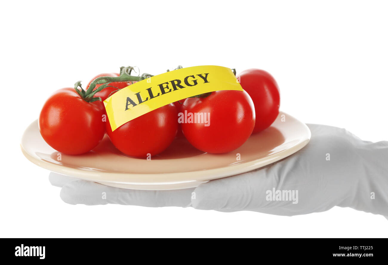 Allergic food concept. Hand in glove holding tomatoes isolated on white ...
